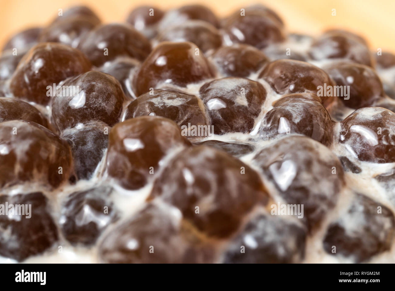 A glass cup of pearl milk tea (also called bubble tea) and a plate of ...