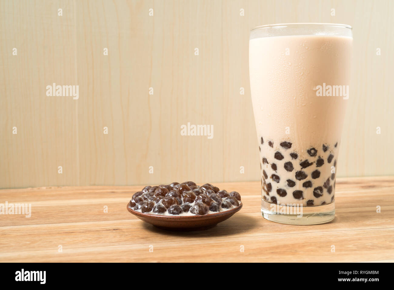 A glass cup of pearl milk tea (also called bubble tea) and a plate of ...
