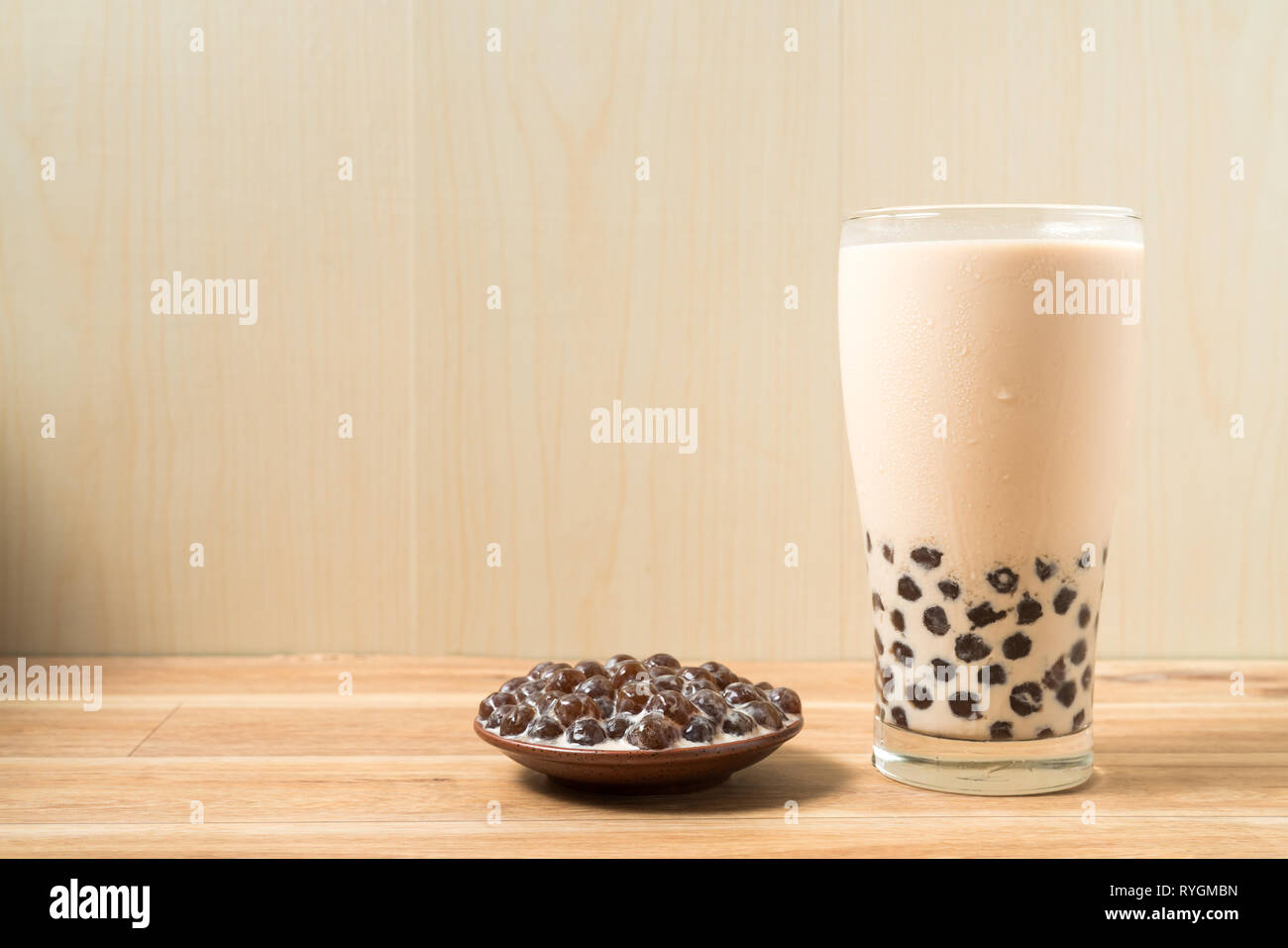 A glass cup of pearl milk tea (also called bubble tea) and a plate of ...