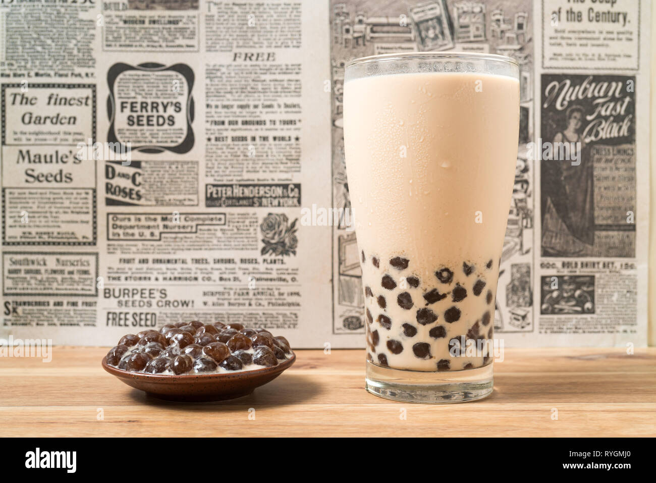 A glass cup of pearl milk tea (also called bubble tea) and a plate of ...