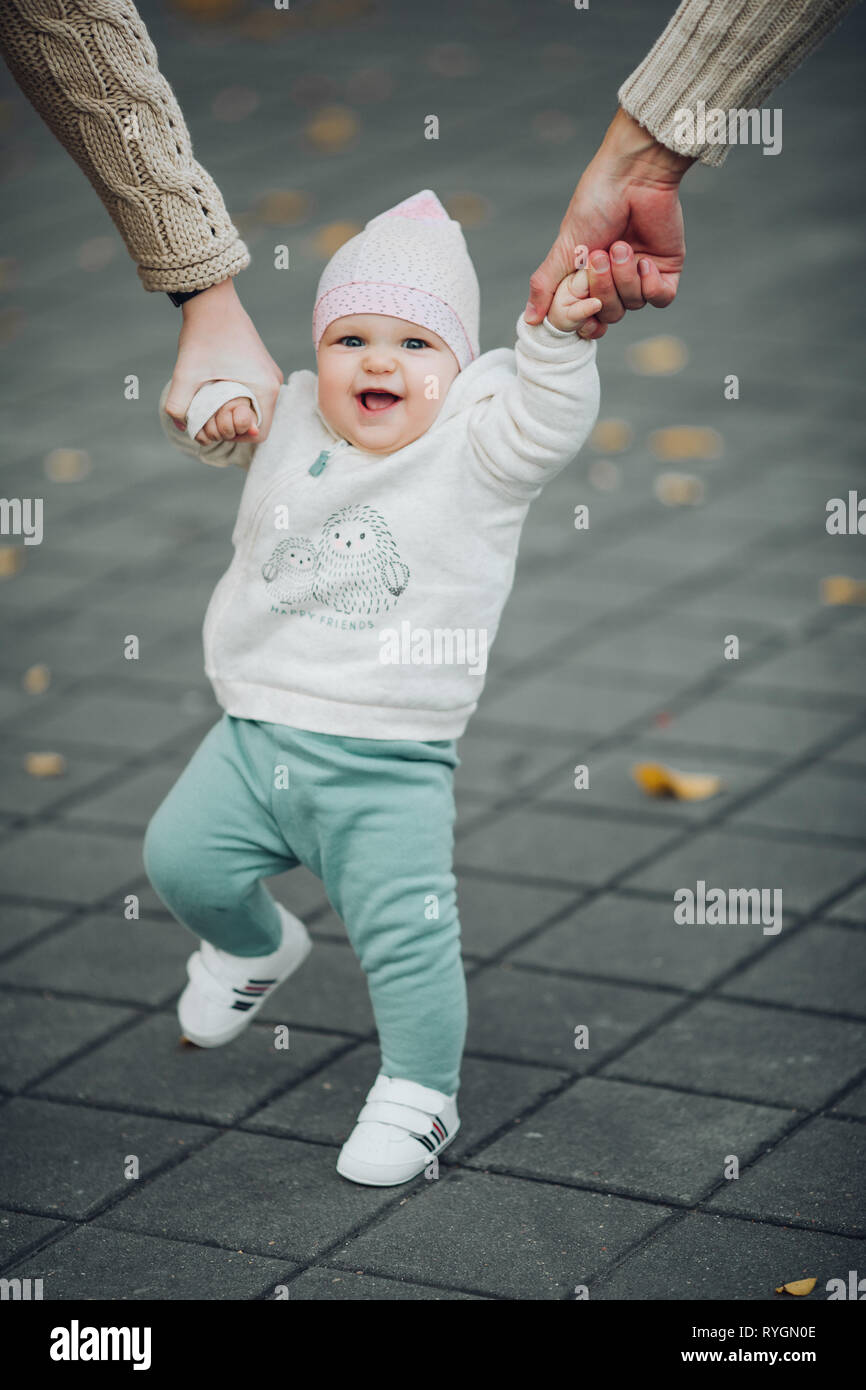 Parents holding satisfied child by hands while it walking Stock Photo ...