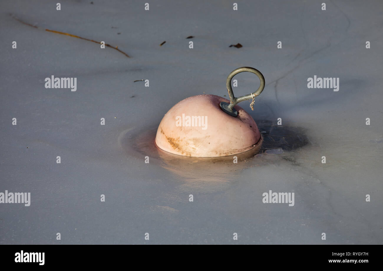 Pink buoy floater frozen in the ice of Lake Malaren, Sweden ...