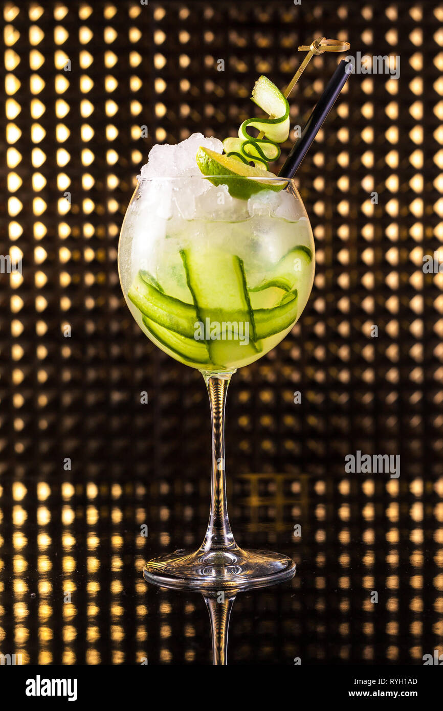 Green fruit cocktail with cucumber in tall round glass with ice cubes ...