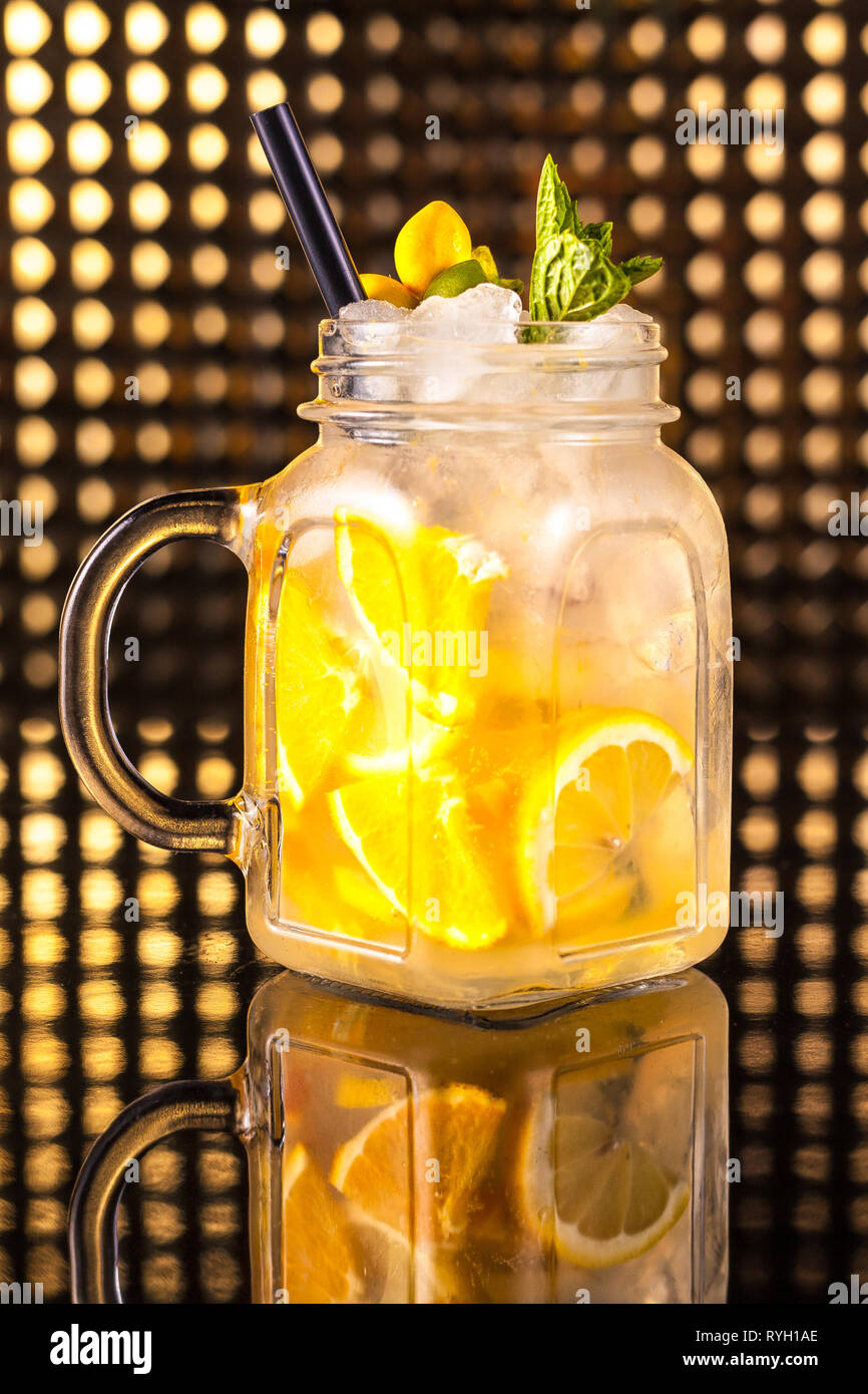 Yellow fruit cocktail lemonade with fresh lemon in vintage jar with ice ...