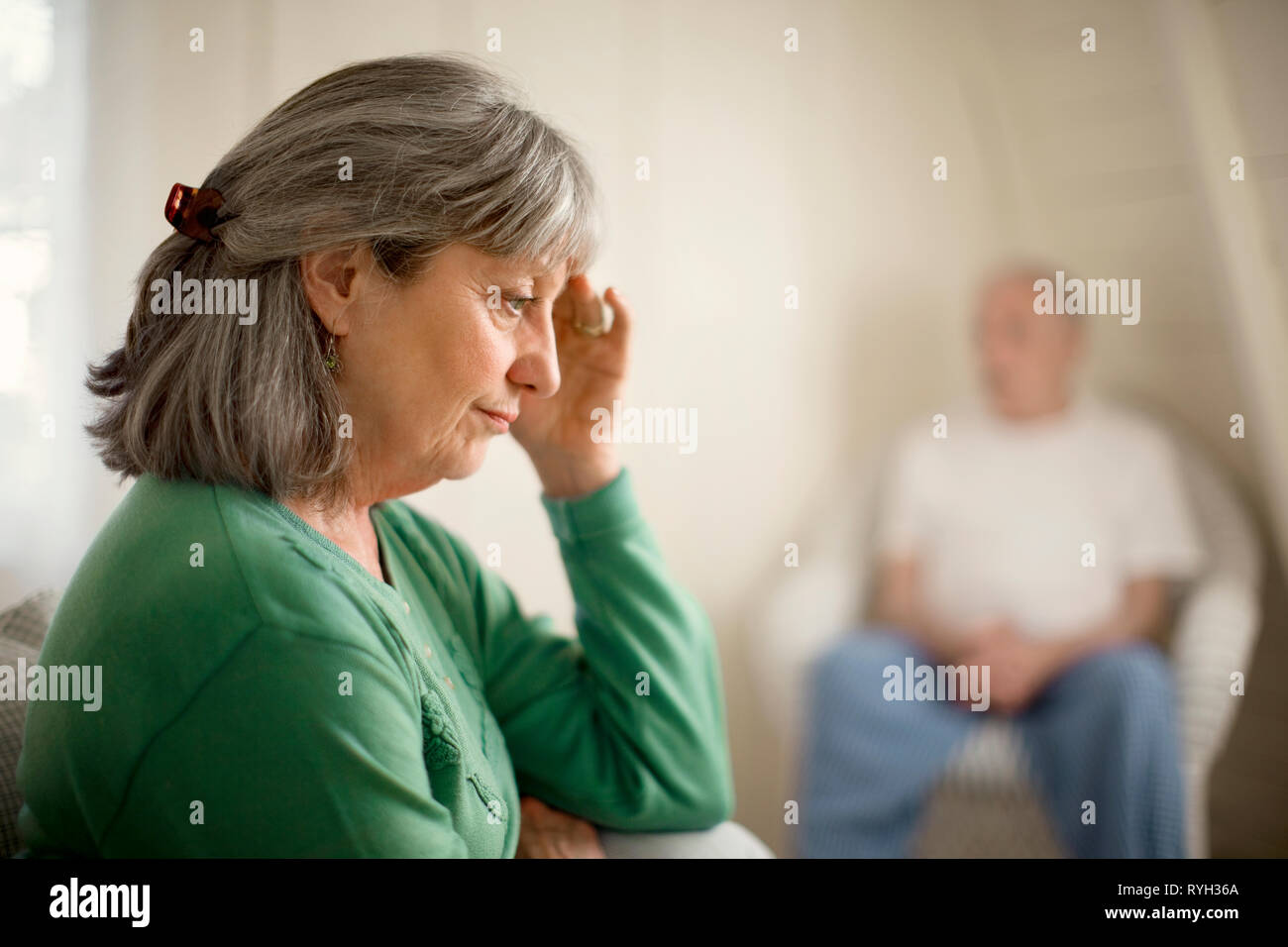 Concerned senior woman sitting in a room with her husband Stock Photo ...