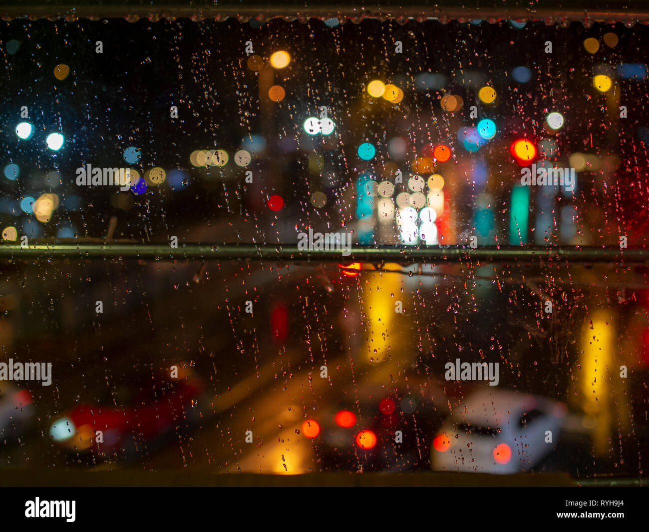 Night lights urban scene. When rainy weather from behind the window ...