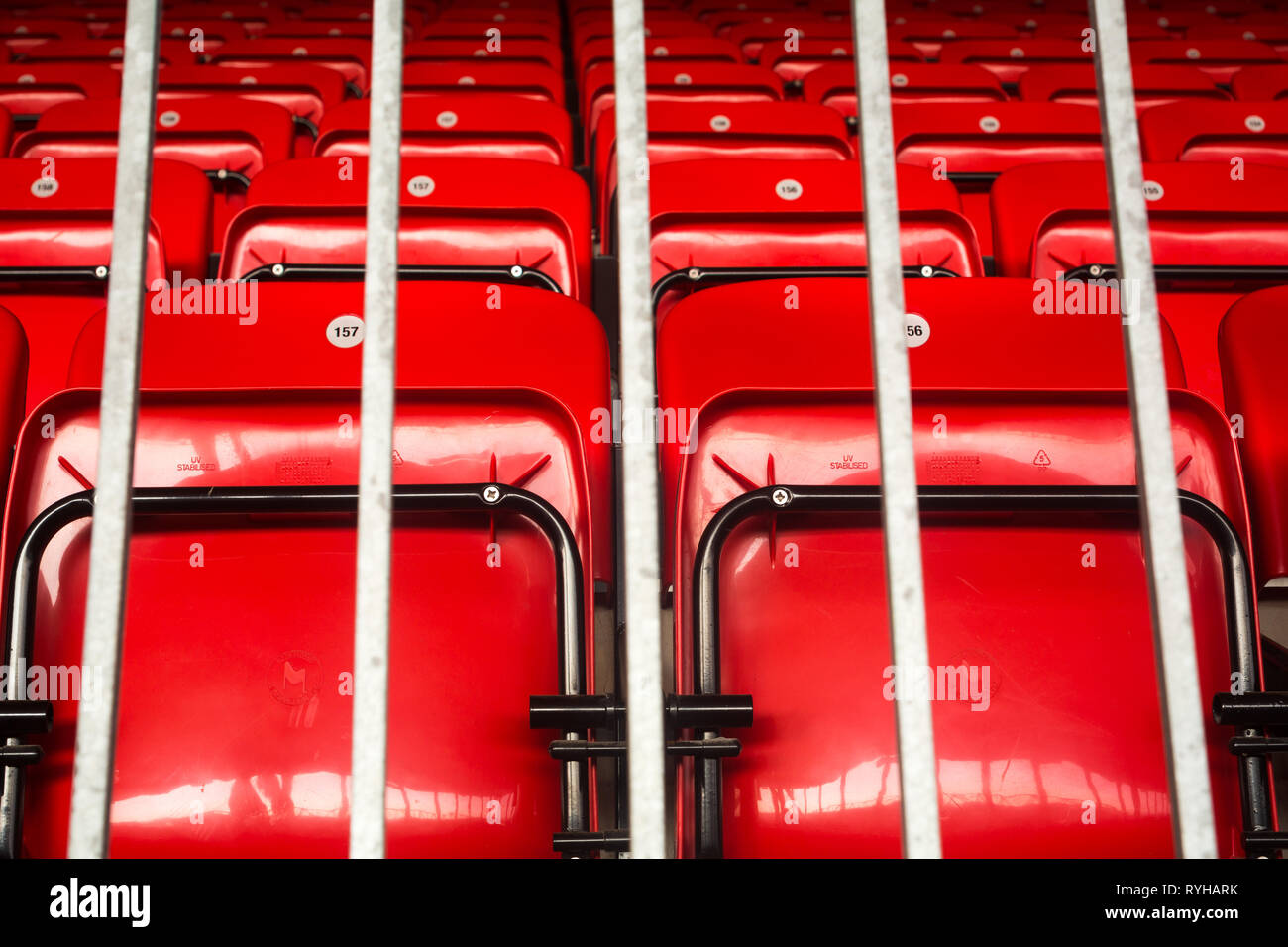 Rows of numbered foldable shiny red plastic seating for fans on ...