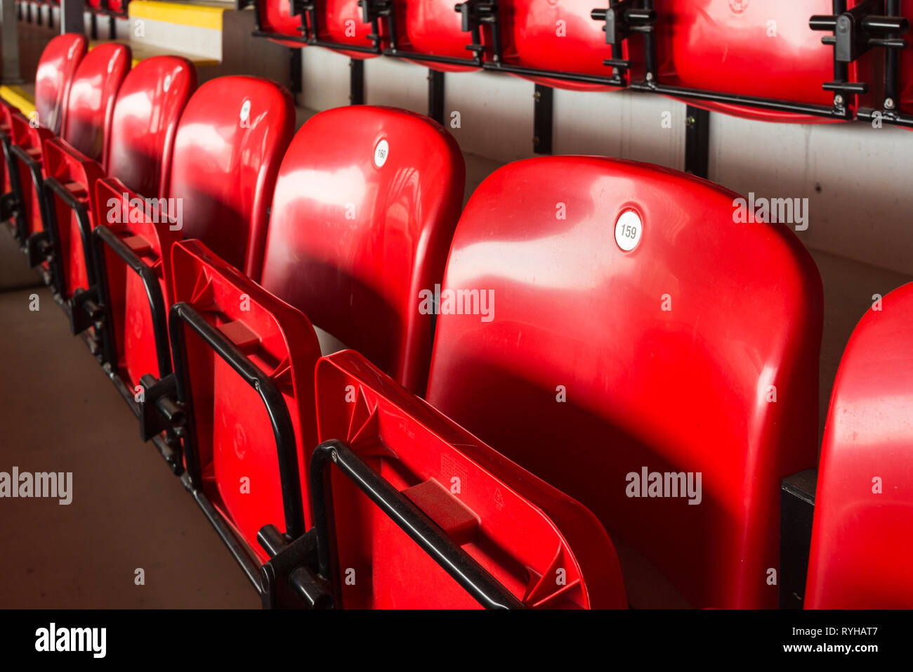 Row of numbered foldable shiny red plastic seating for fans on terraces ...
