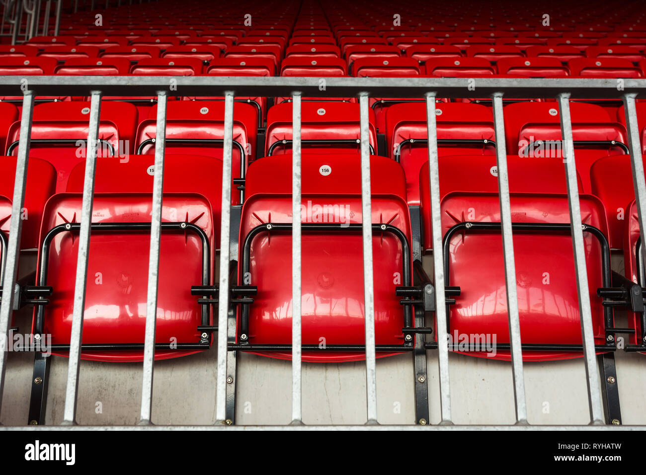 Rows of numbered foldable shiny red plastic seating for fans on ...