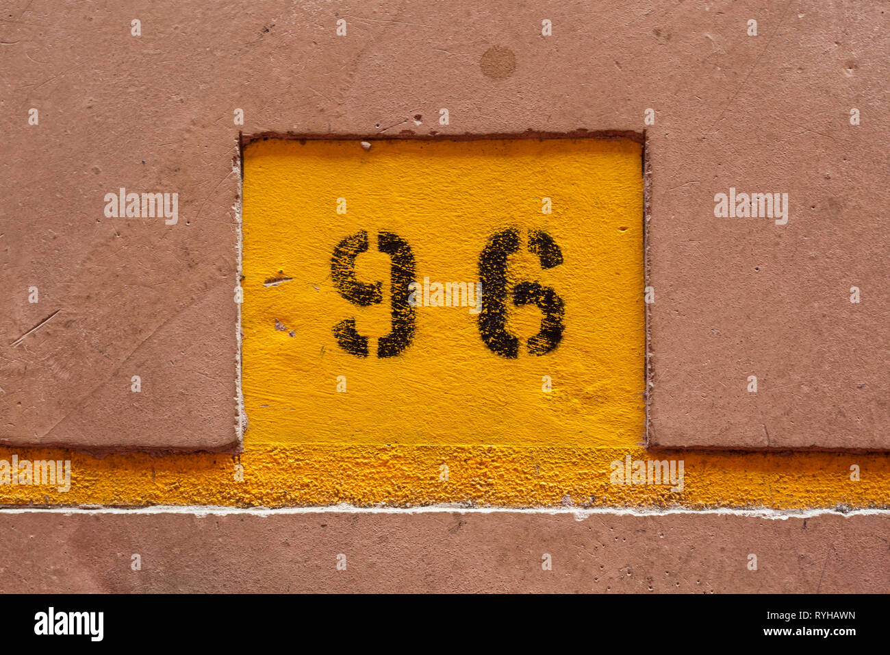 Number 96 stencilled in black paint on yellow background on floor of ...