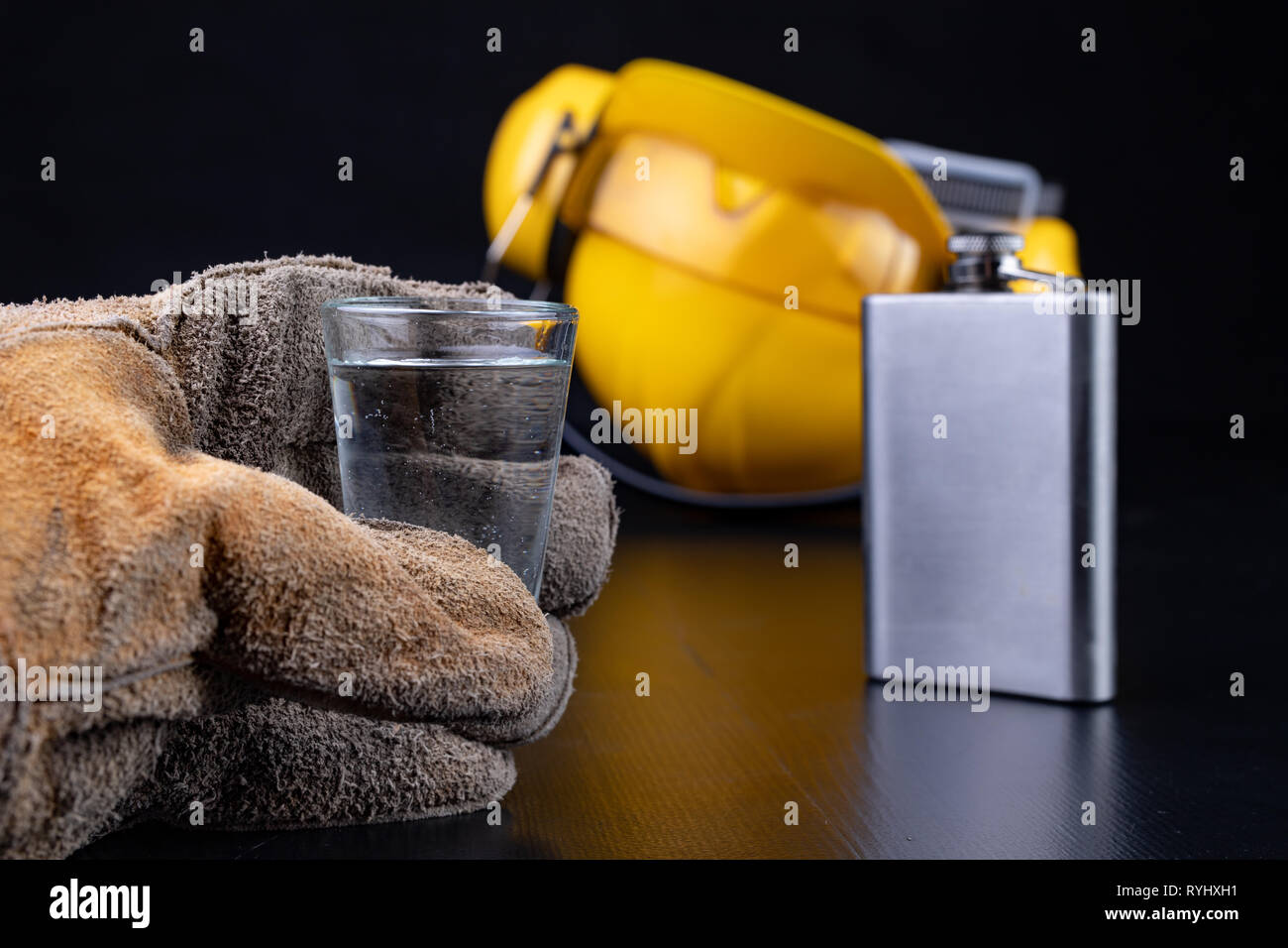A shot of vodka and a bottle on a workshop table. Workwear and alcohol ...