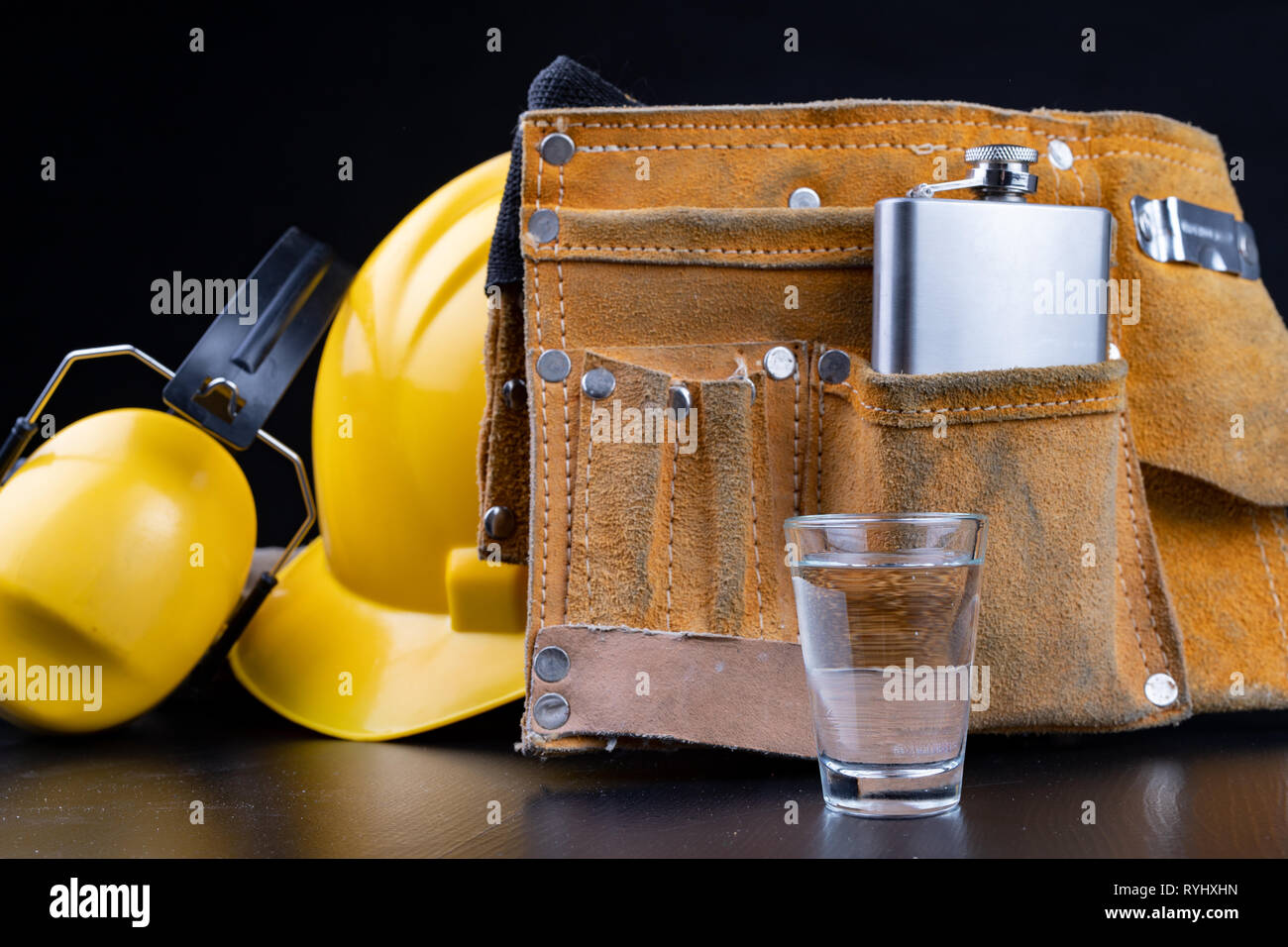 A shot of vodka and a bottle on a workshop table. Workwear and alcohol ...