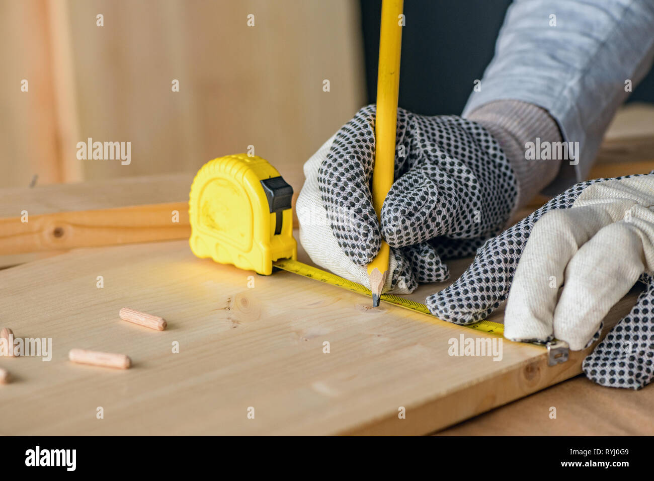 Carpenter marking pine wood plank for cutting in woodwork workshop ...