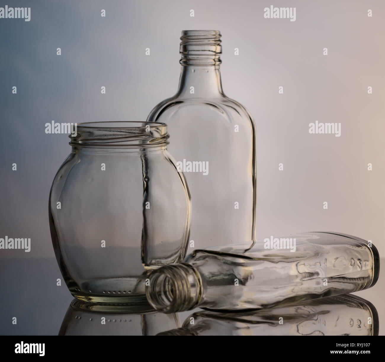 Still life. Glass to clear. Glass bottles and jars on a colored ...