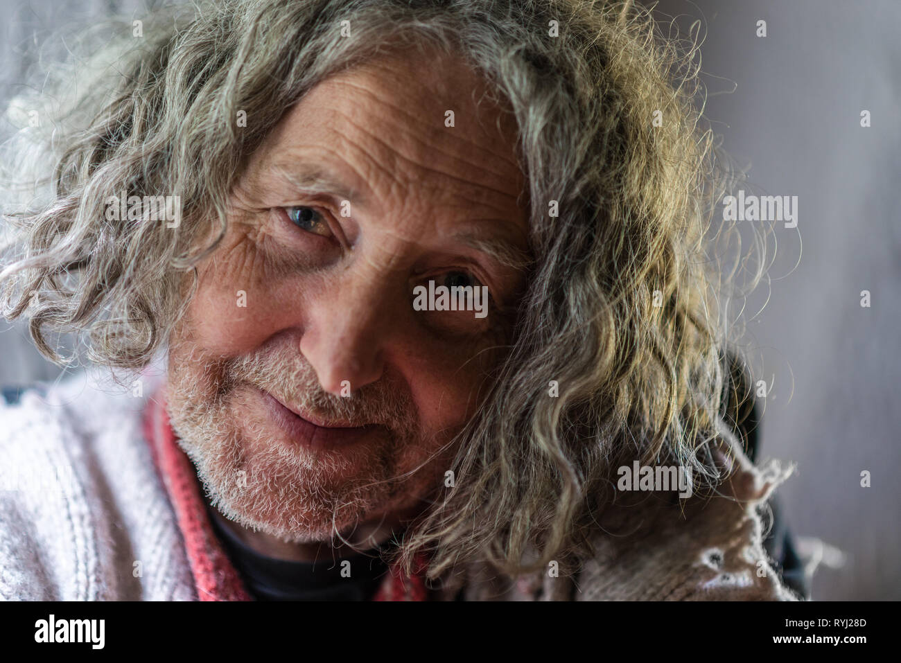 Portrait of an old man with grey curly hair with kind sincere look in ...