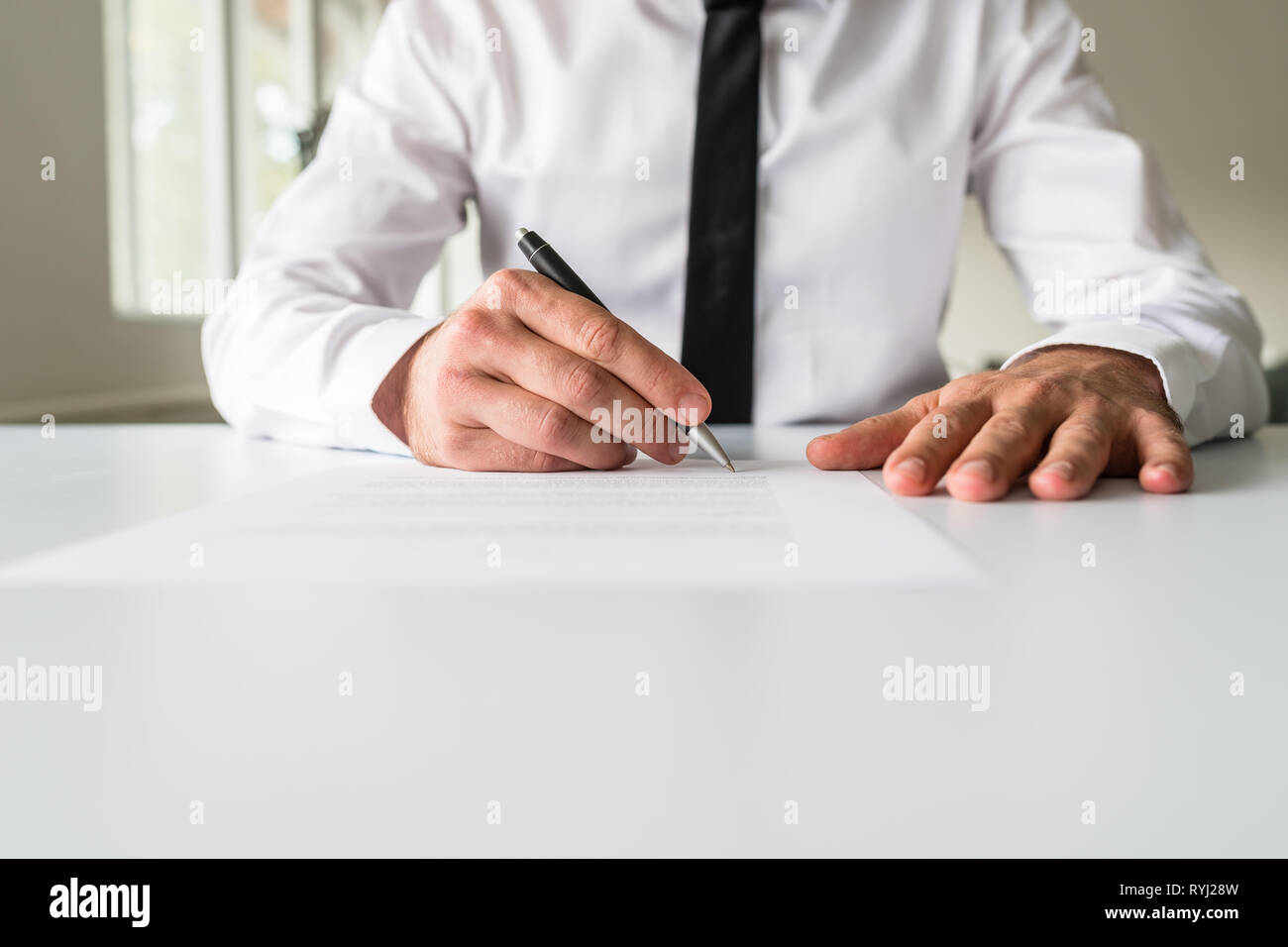 Front view of businessman at his office desk signing a document ...