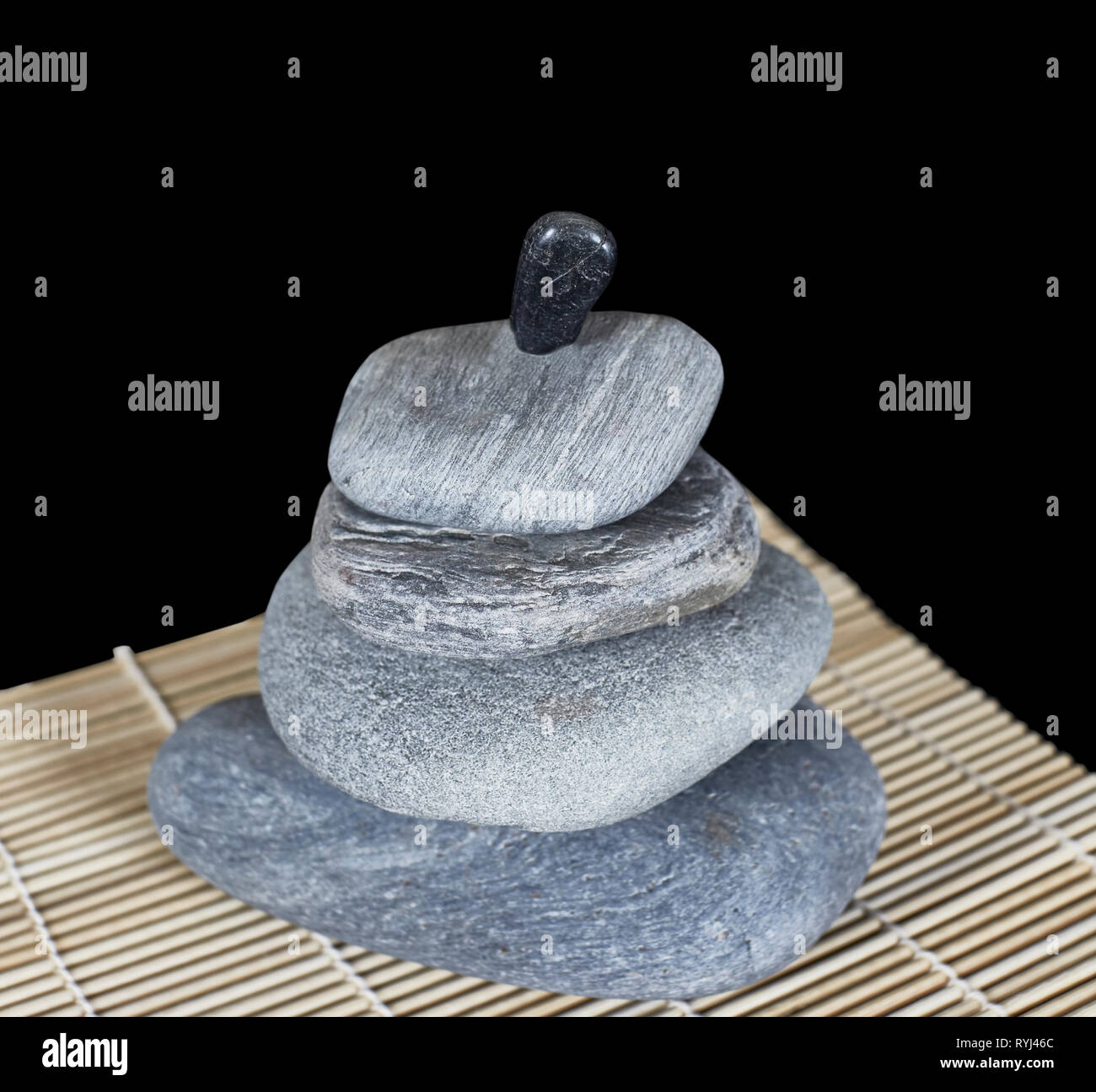 River rocks balanced on one another sitting on bamboo mat isolated on ...