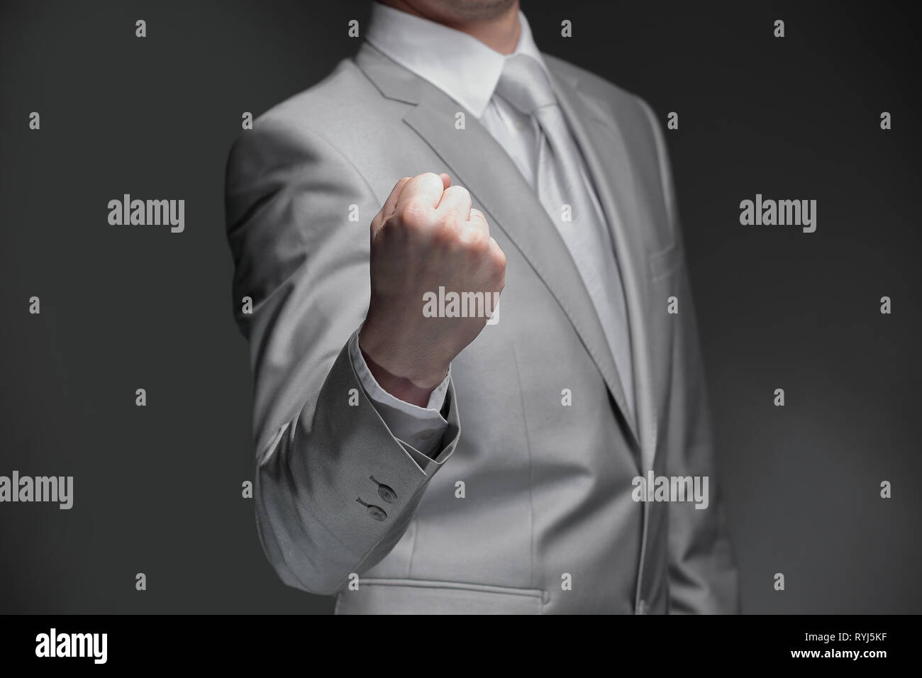 close up.businessman clenching his hand in a fist .isolated on black ...