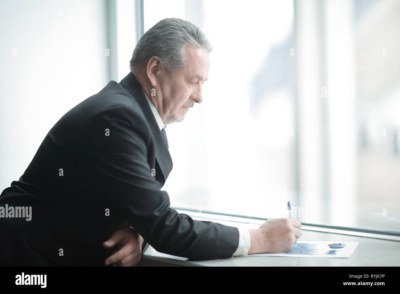 businessman signs a document, standing near the office window Stock ...