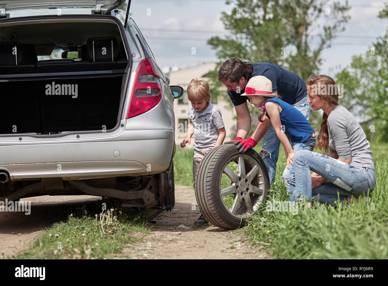 children help their father to replace the car tire Stock Photo - Alamy