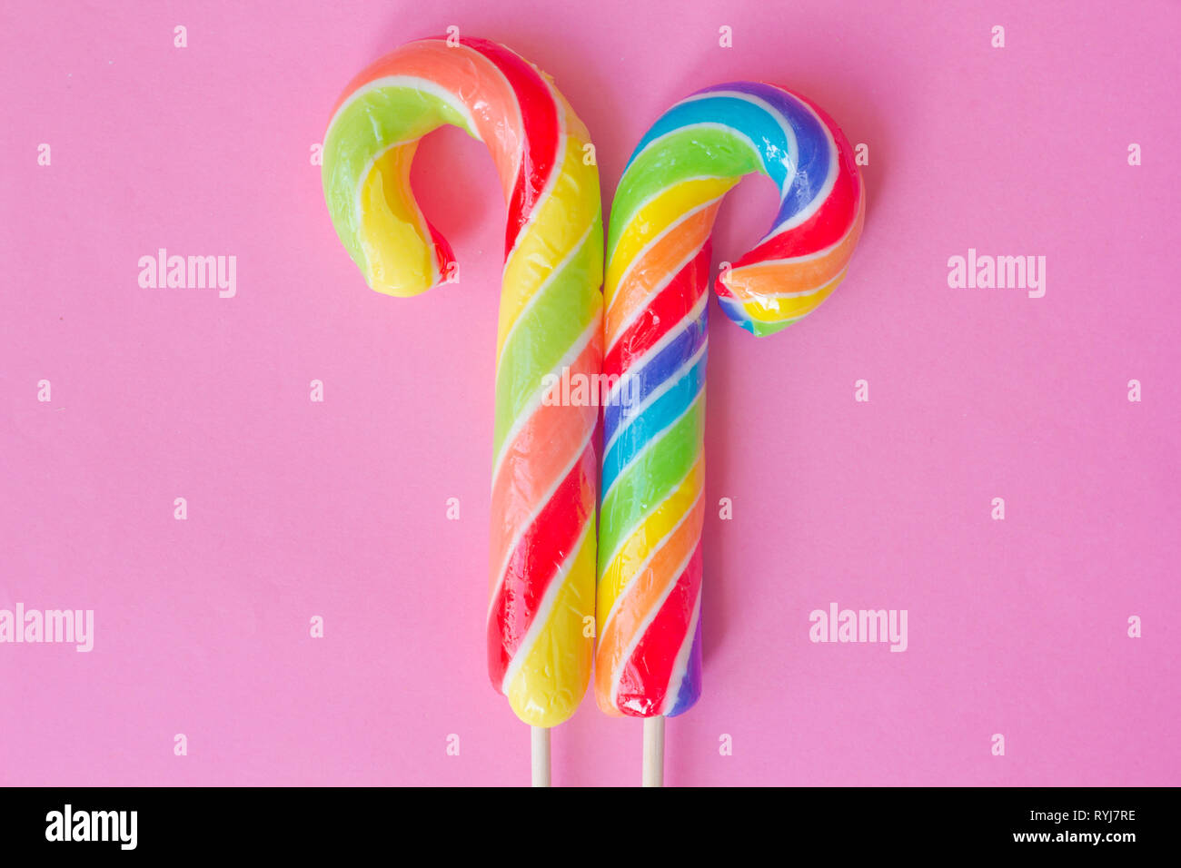 Colored caramel on a stick. Caramel on a pink background. Isolated pink ...