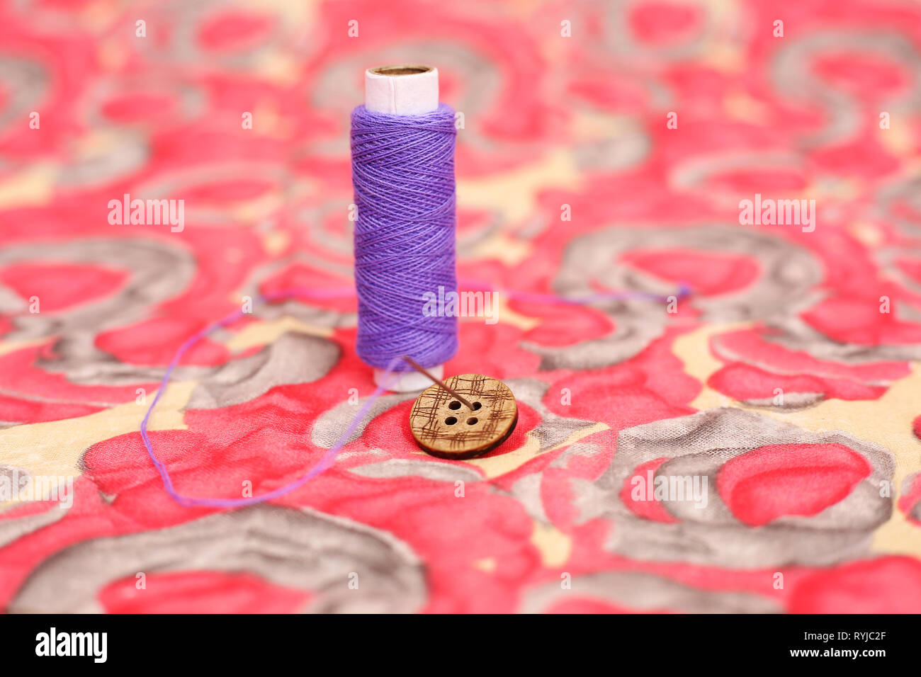 Picture of purple sewing thread, needle and button. Isolated on the ...