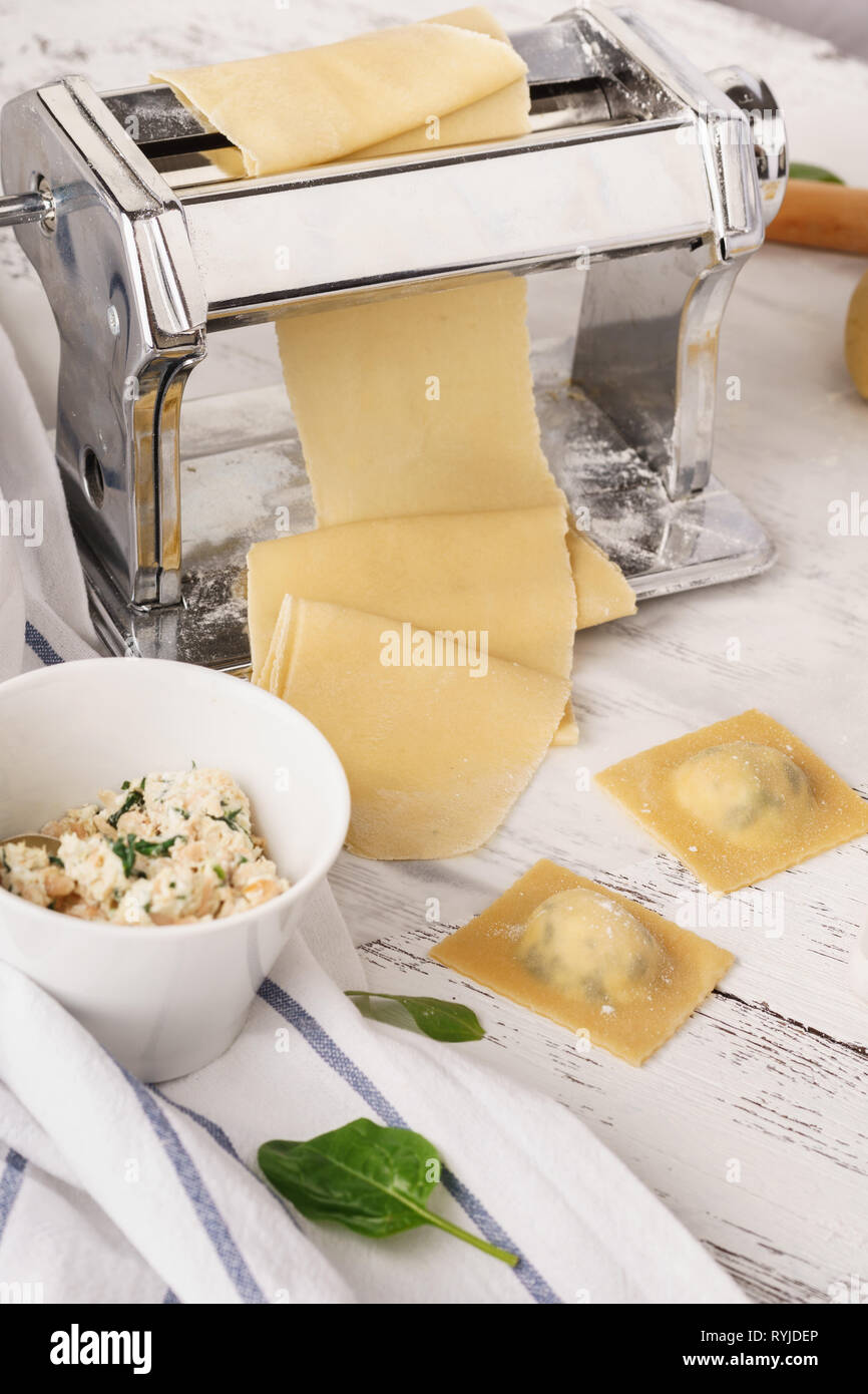 Pasta machine and fresh homemade uncooked ravioli with filling. Italian ...