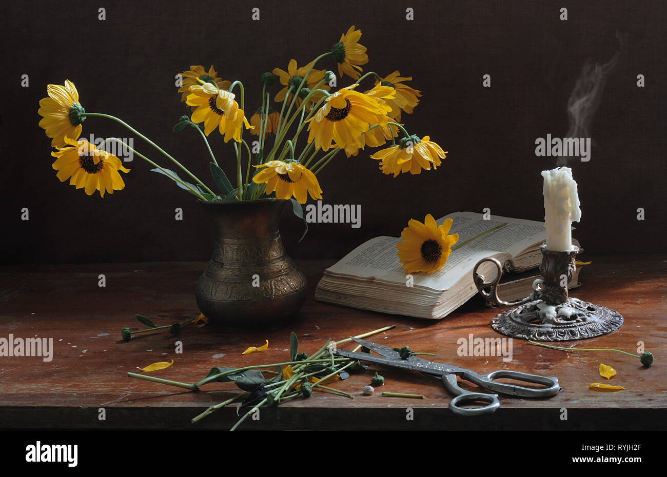 Still life with yellow flowers, a book and a candle Stock Photo - Alamy