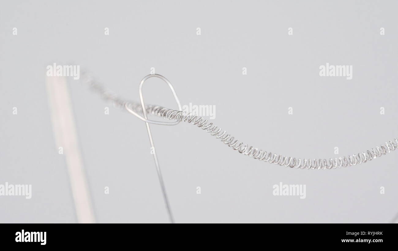 Silver coils on a macro shot that looks like a spring with two wires on ...