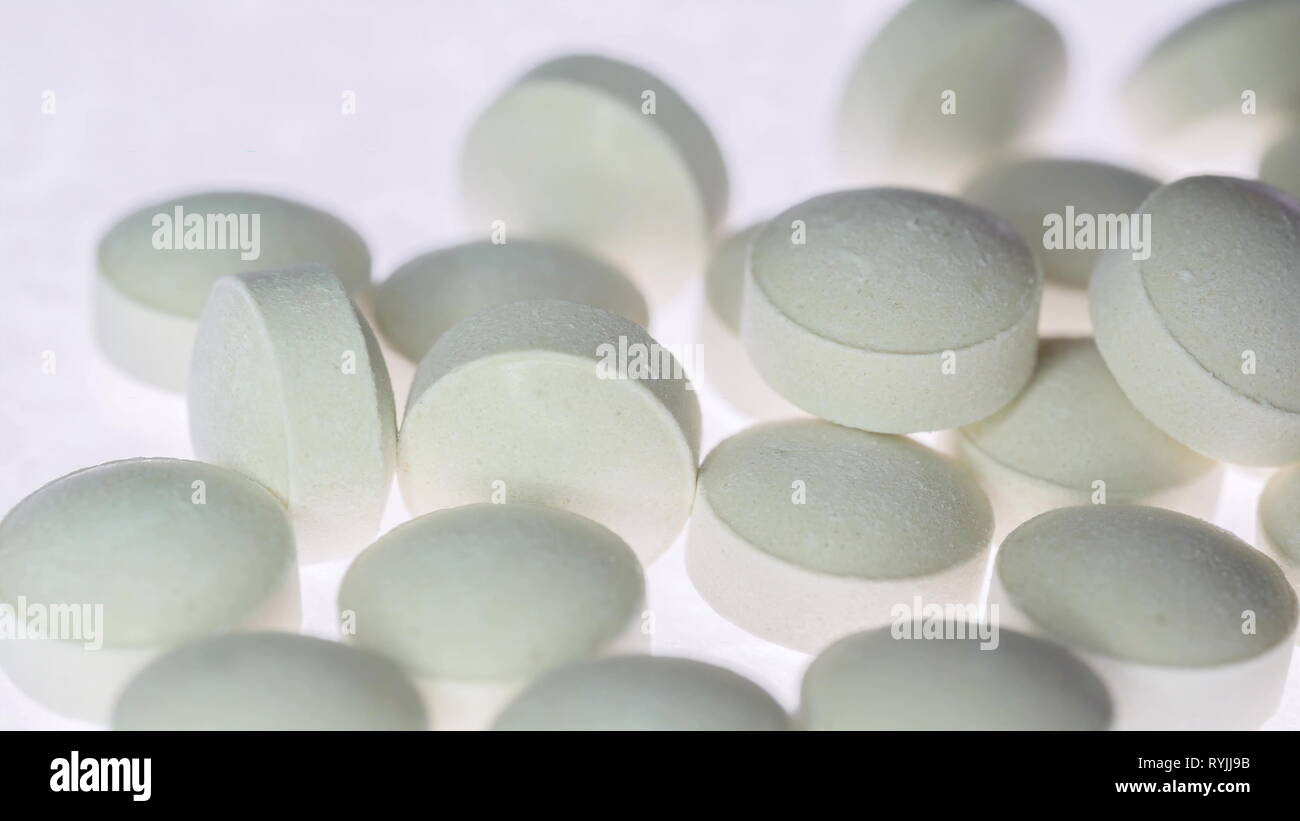 Tiny white medicine tablets on a macro shot from the table top Stock ...