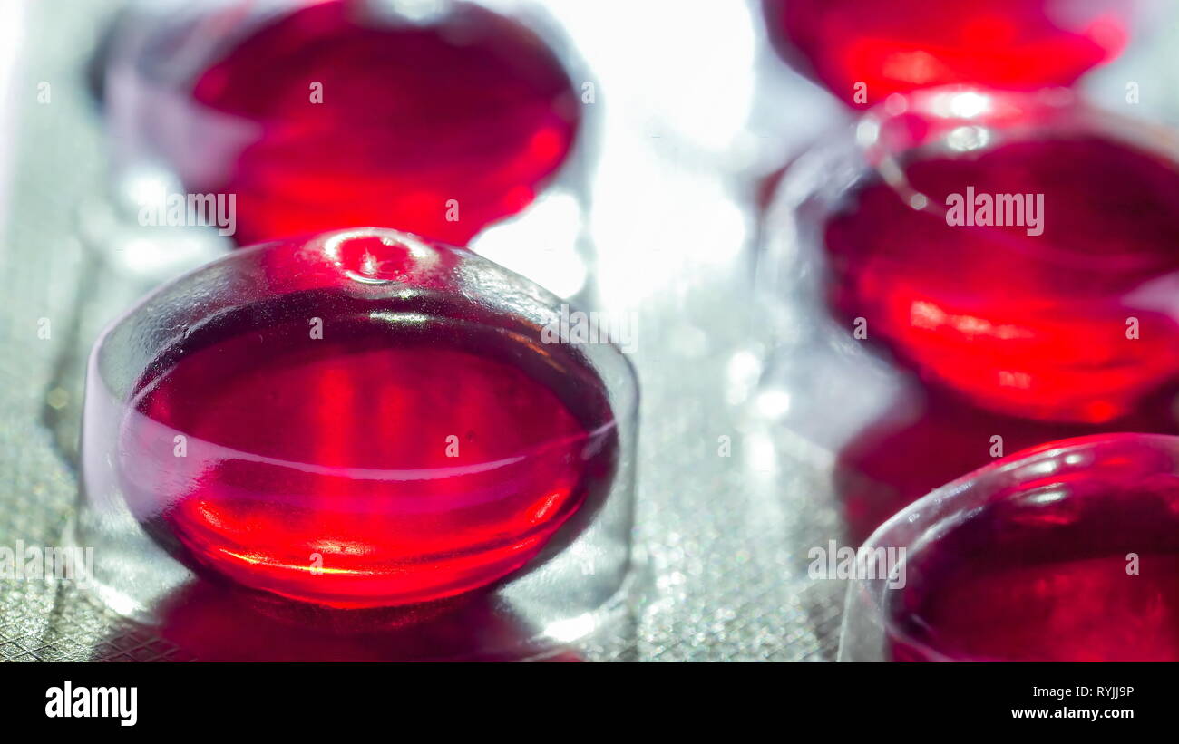 Plastic cover on the red capsules on a macro shot from the medicine ...