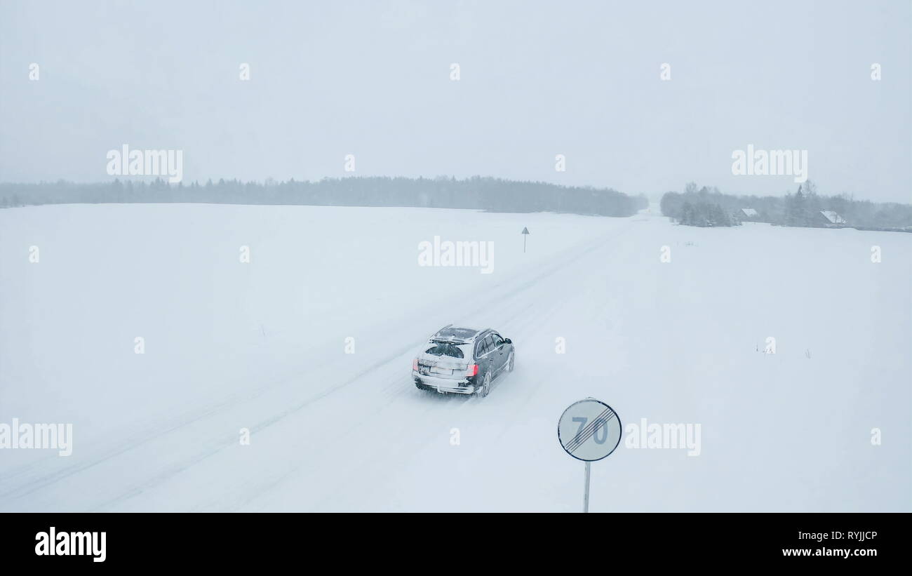 Snow is raining on the ground in an aerial view with the car running on ...