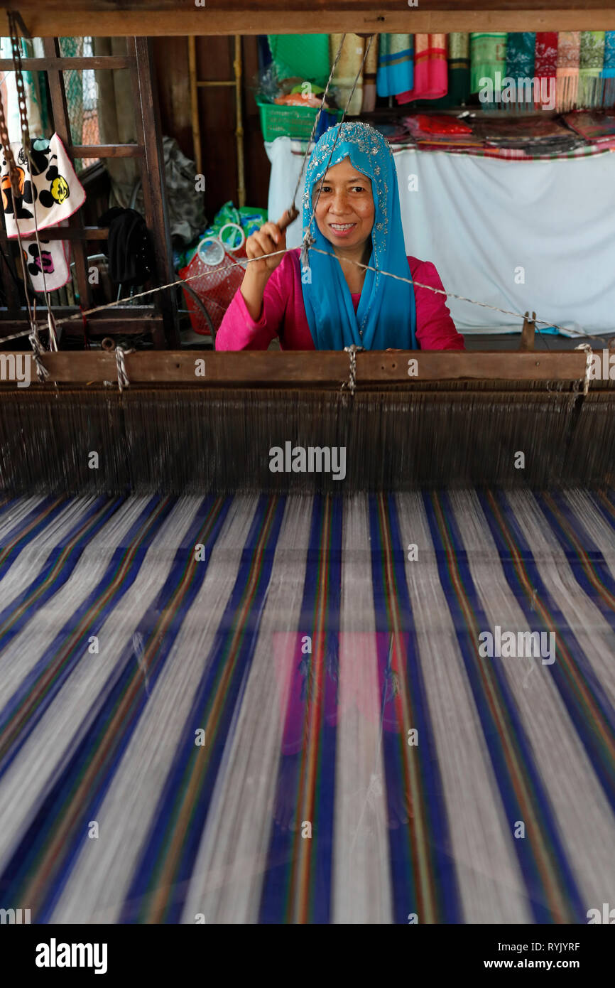 Traditional hand loom. Local muslim woman diligently weaving colourful ...
