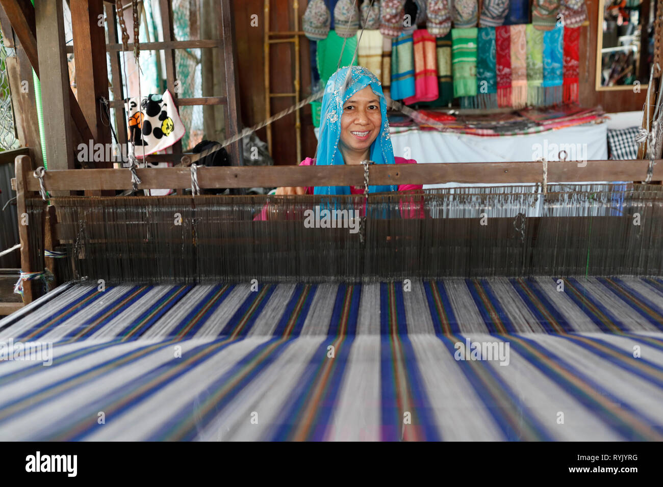 Traditional hand loom. Local muslim woman diligently weaving colourful ...