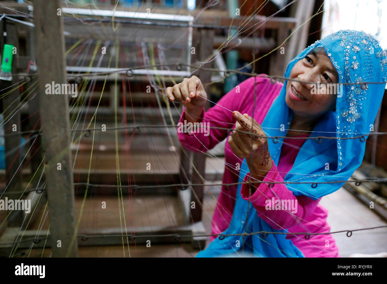 Traditional hand loom. Local muslim woman diligently weaving colourful ...