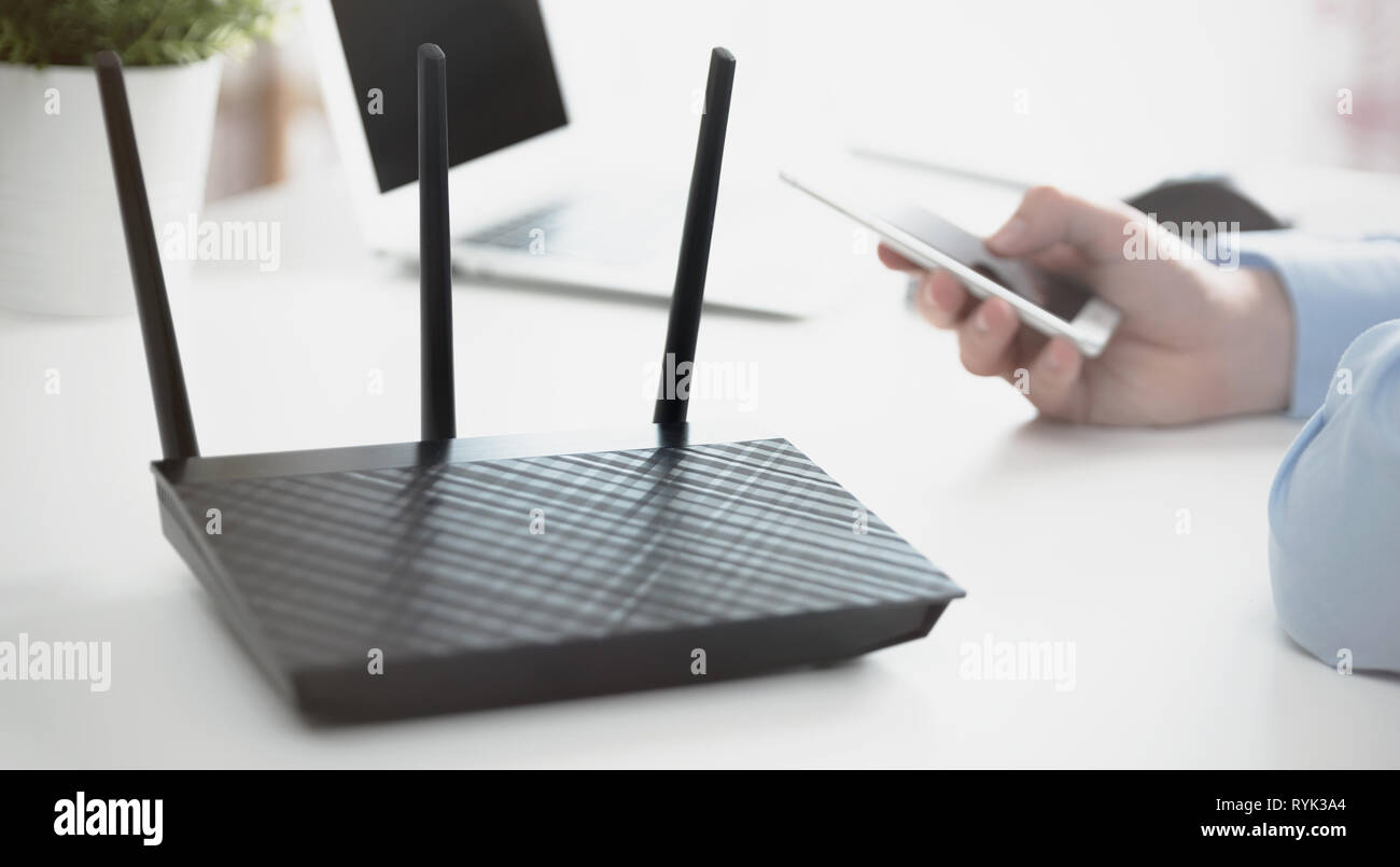 Wireless router or access point. Man using smartphone Stock Photo - Alamy