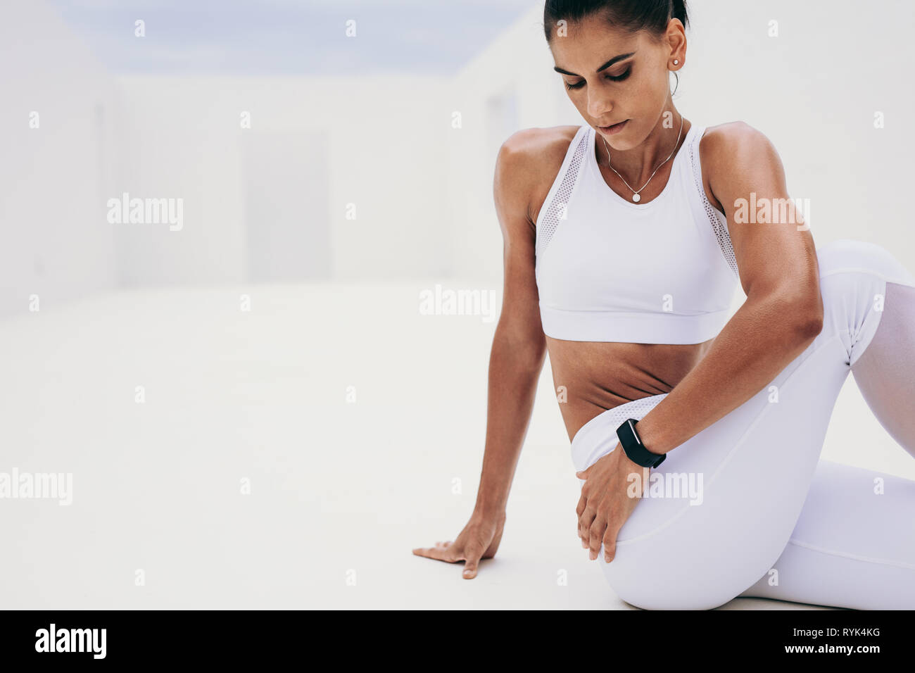Athletic woman sitting on floor and doing stretching exercises. fitness ...