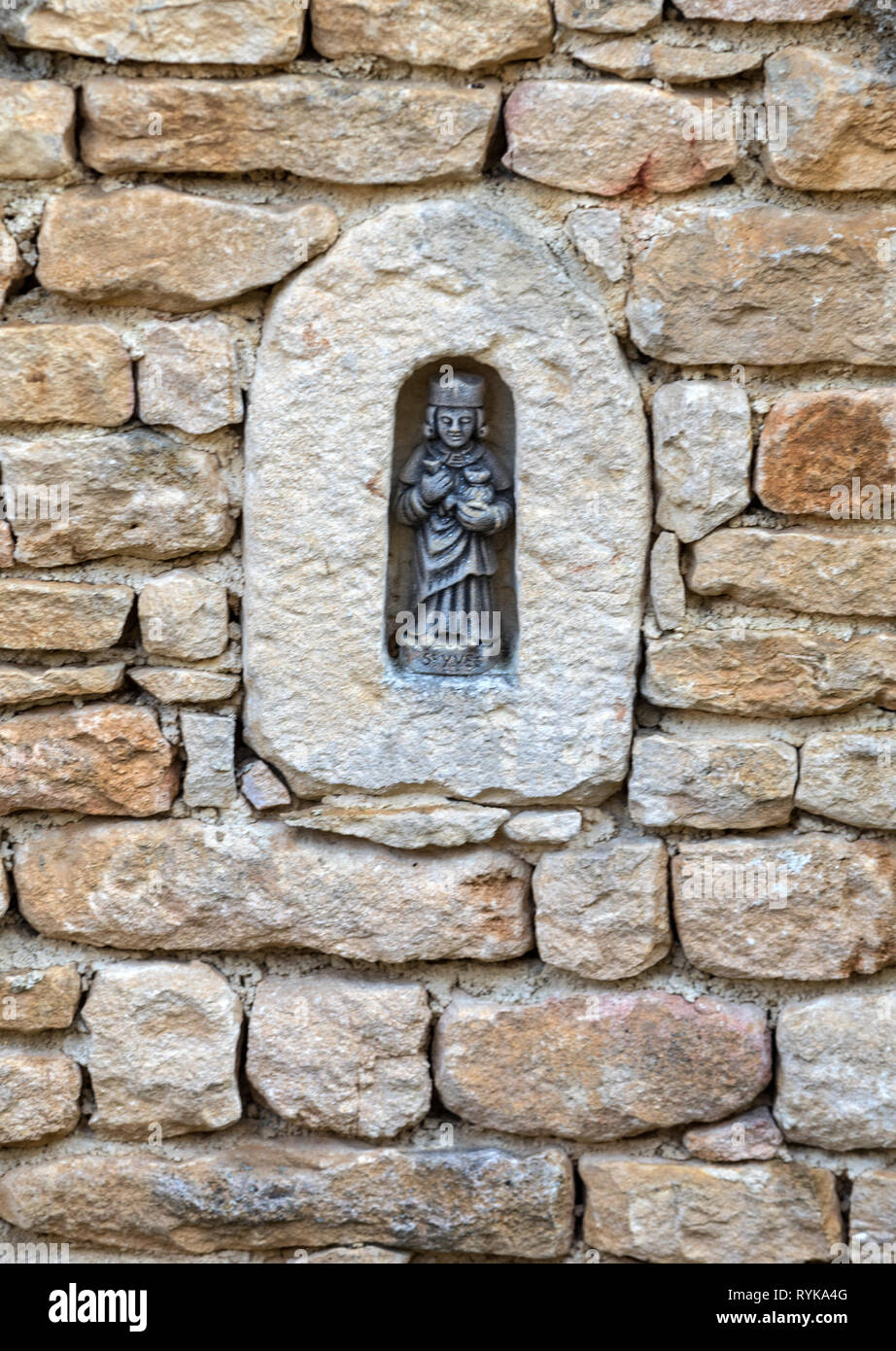Medieval stone wall with a small statue of religious saint in Domme ...