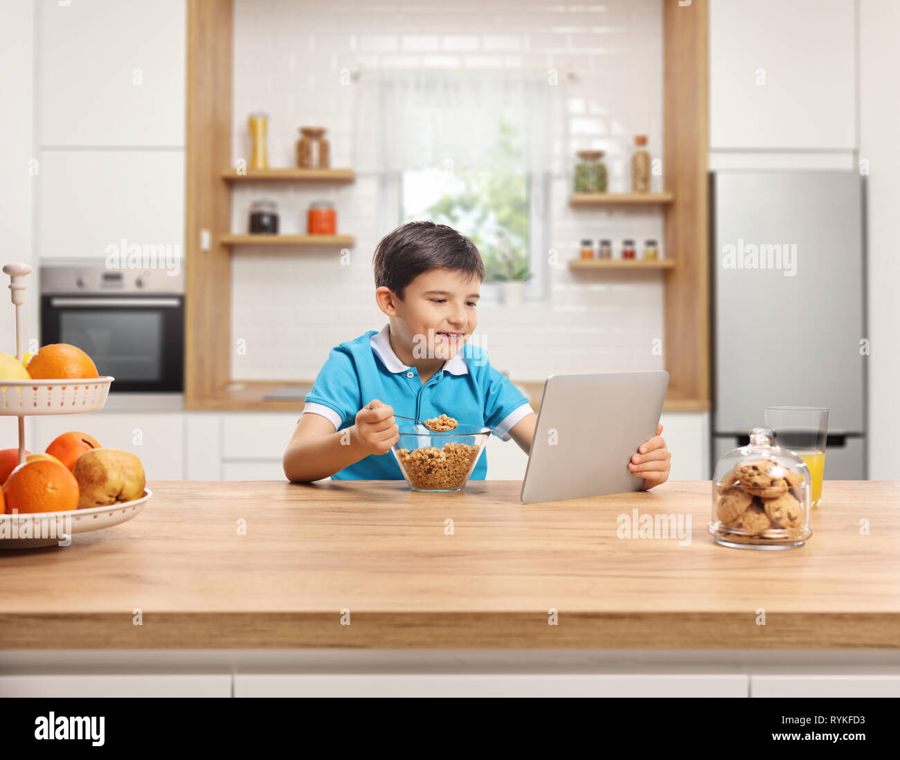 Little boy eating cereals for breakfast at a wooden counter and ...