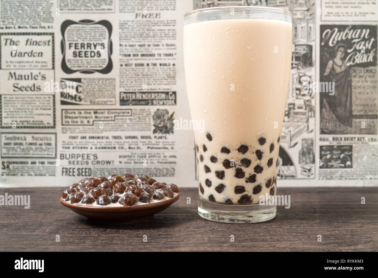 A glass cup of pearl milk tea (also called bubble tea) and a plate of ...