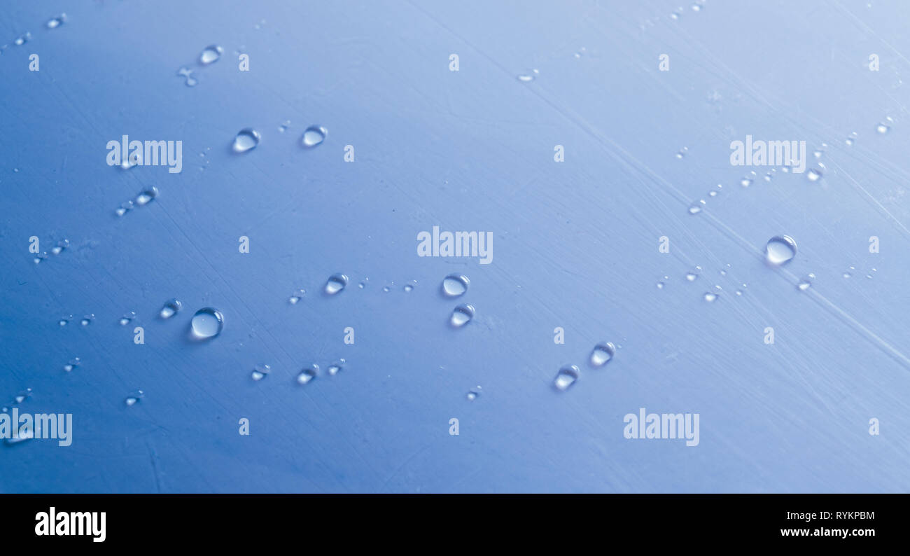 Close-up of a smooth, metallic blue surface with lots of water drops ...