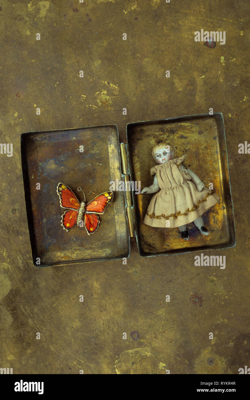 Miniature dressed Victorian doll lying in small tarnished brass box ...