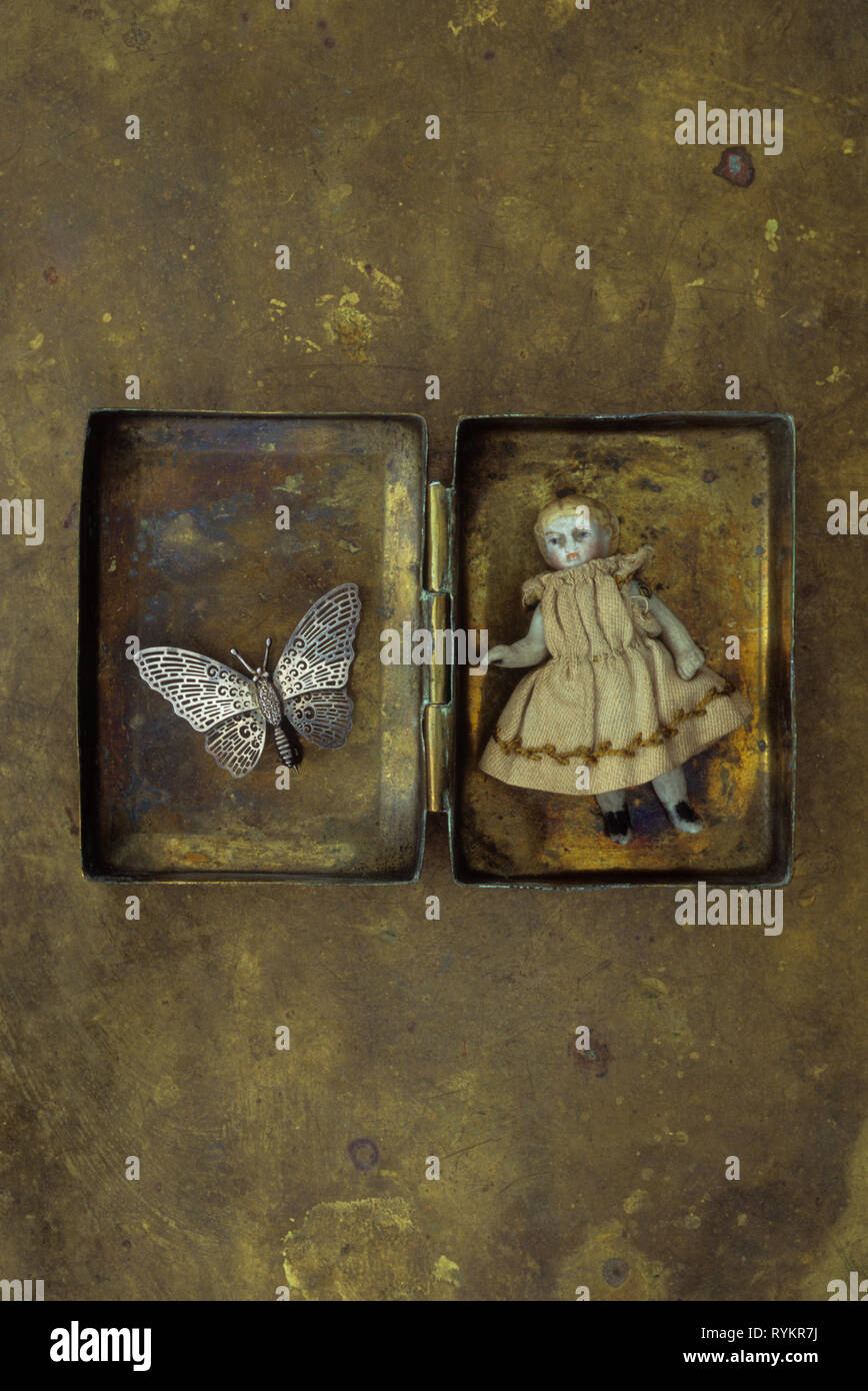 Miniature dressed Victorian doll lying in small tarnished brass box ...