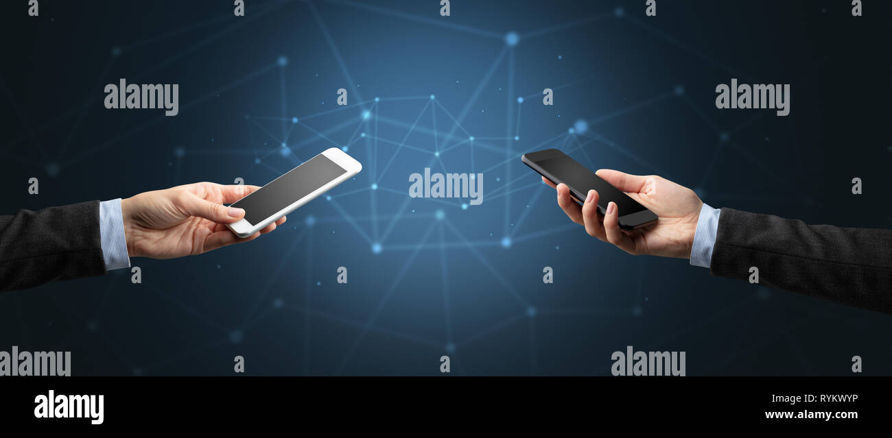 Close up of two hands holding smartphones to each other, wireless ...