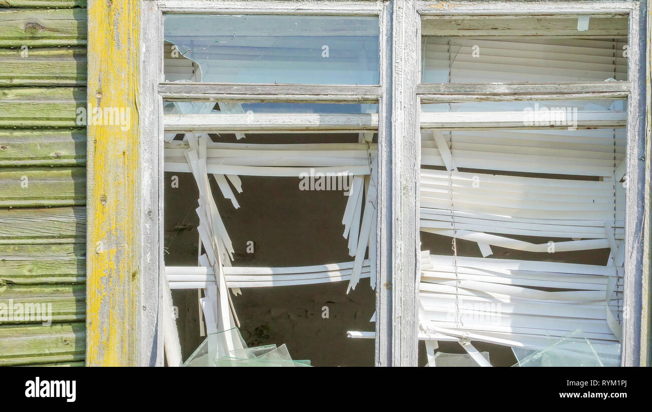 The broken white venetian blinds on the window of a ruined house in the ...