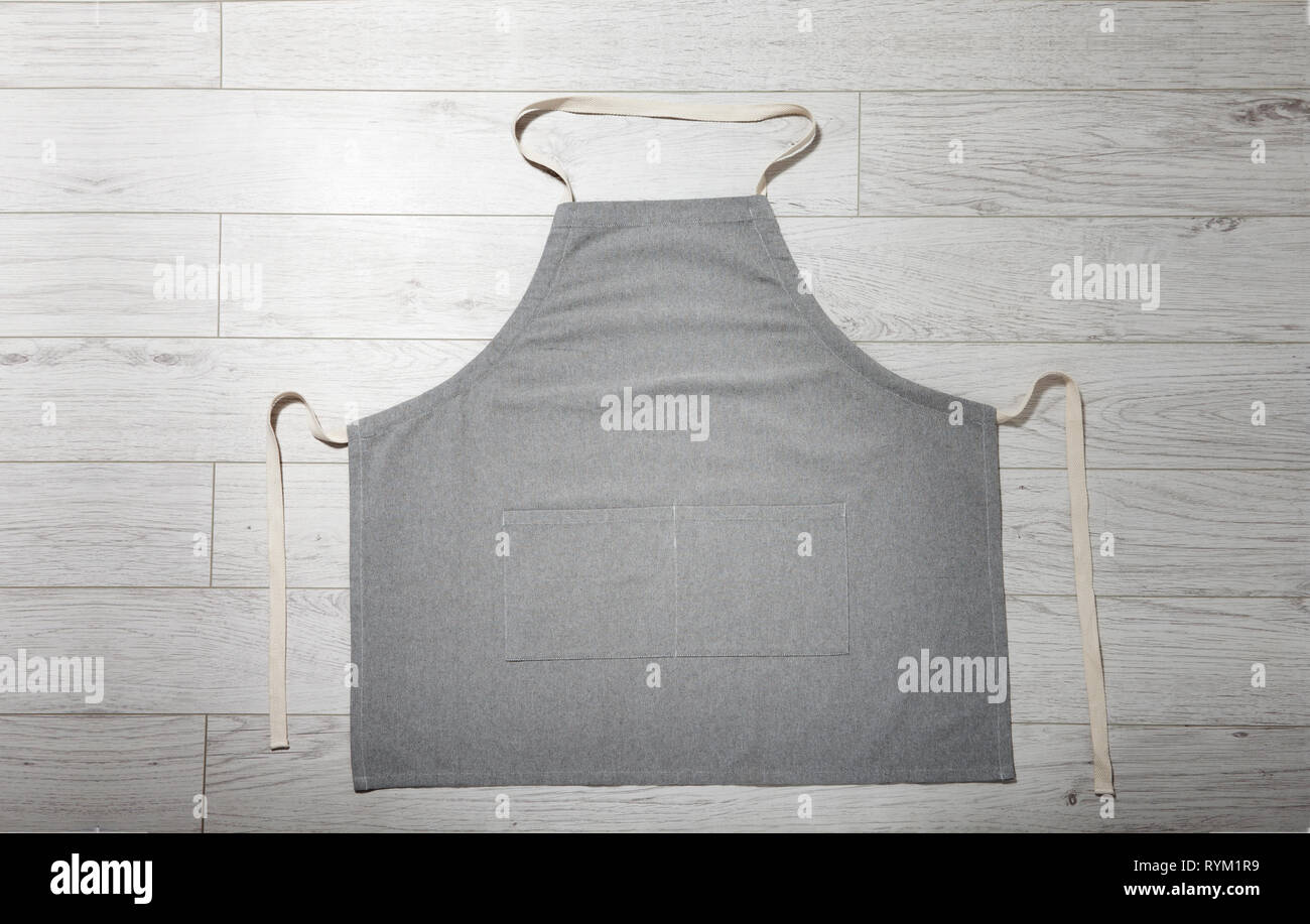 Gray apron for kitchen top view on white wooden background. Mock up ...