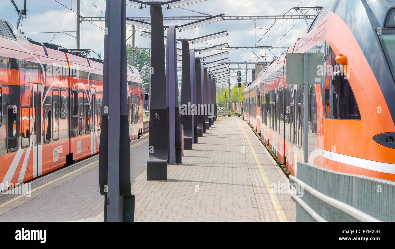 Two orange train on the railway stations in the city boarding some ...