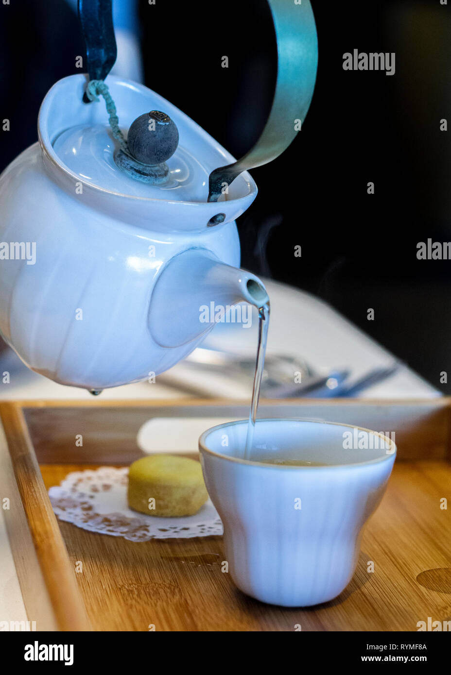 White tea pot pouring onto ceramic cup. Tea setting Stock Photo - Alamy