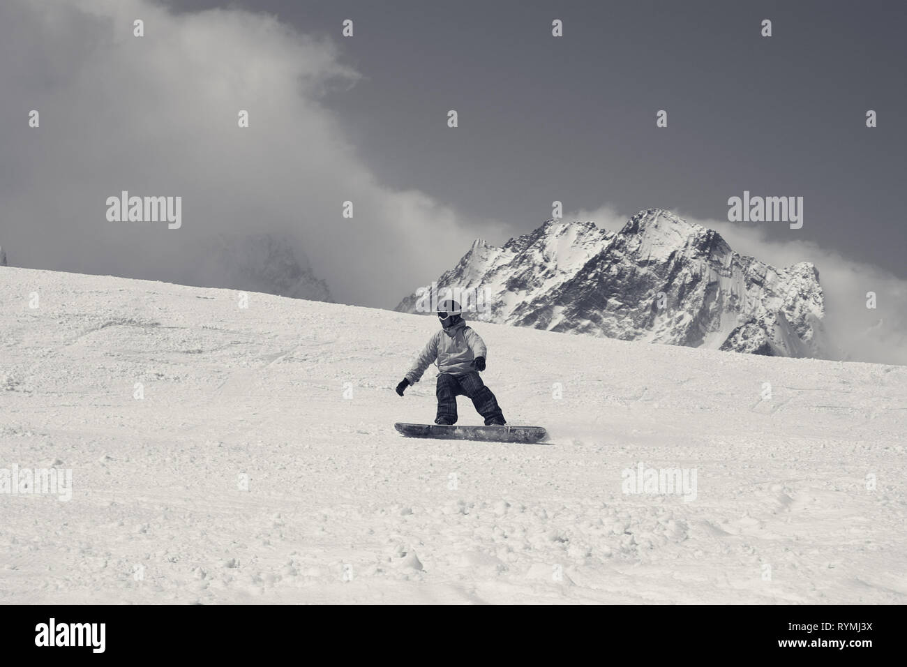 Snowboarder downhill on ski slope in high snowy mountains at sun winter ...