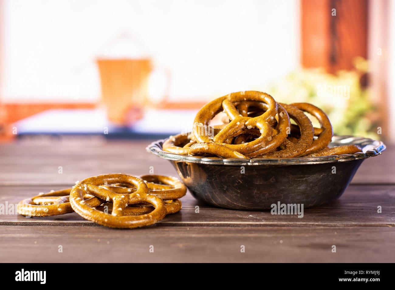 Lot of whole mini salted pretzels stack in old iron bowl with books ...